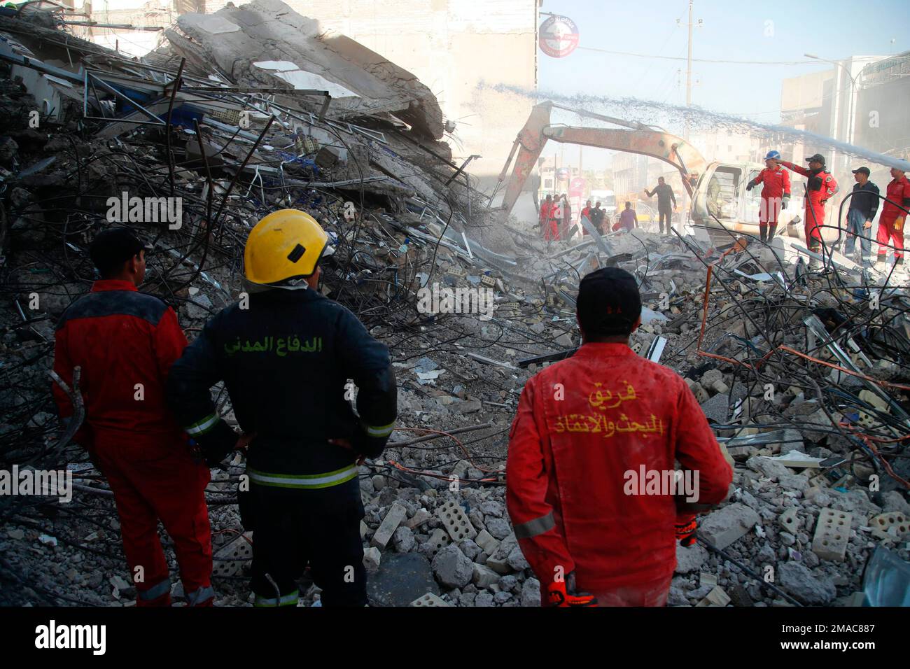 Iraqi emergency and rescue personnel search for survivors in the rubble ...