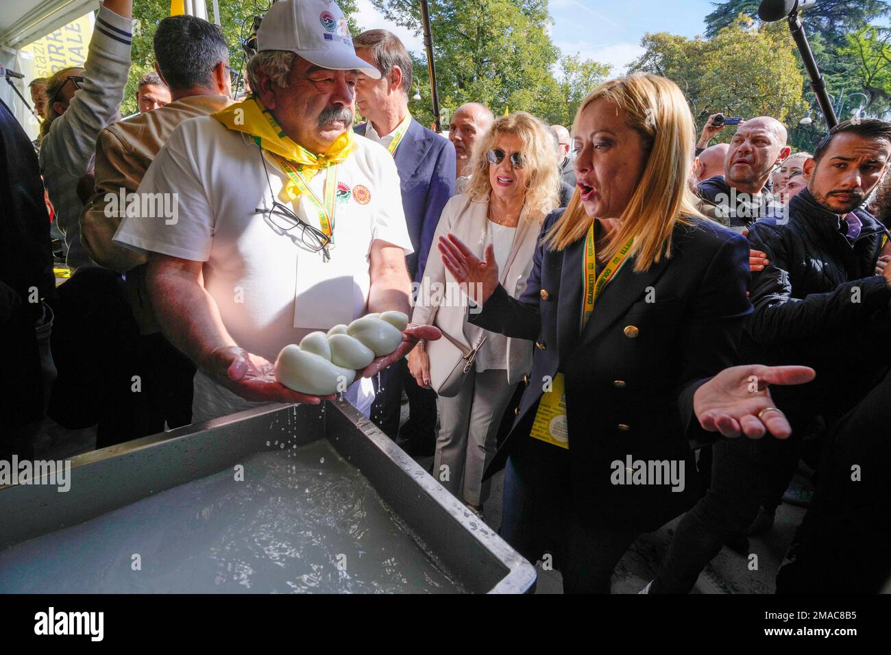 Brothers of Italy leader Giorgia Meloni looks at a farmer making ...