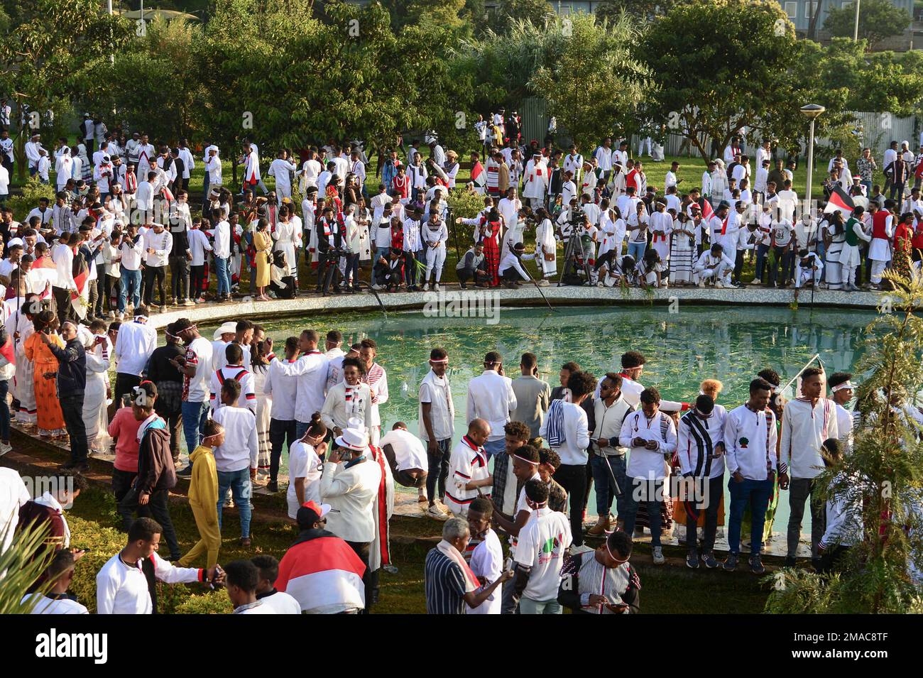 People throw grass and flowers into a pool of water as they celebrate ...