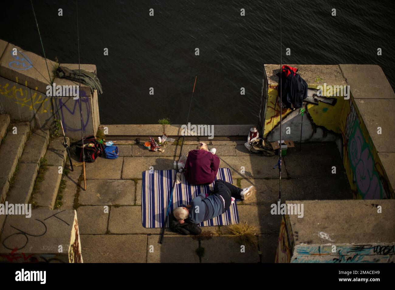 A couple gets some rest as they fish into the Dnipro river in Kyiv ...