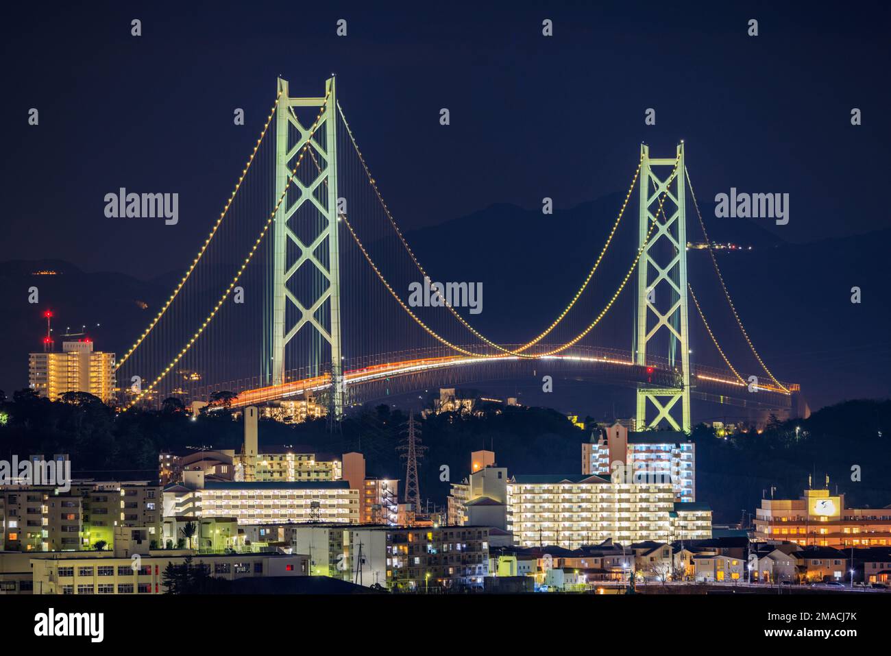 Illuminated Suspension Bridge Towers Over Apartment Buildings at Night ...