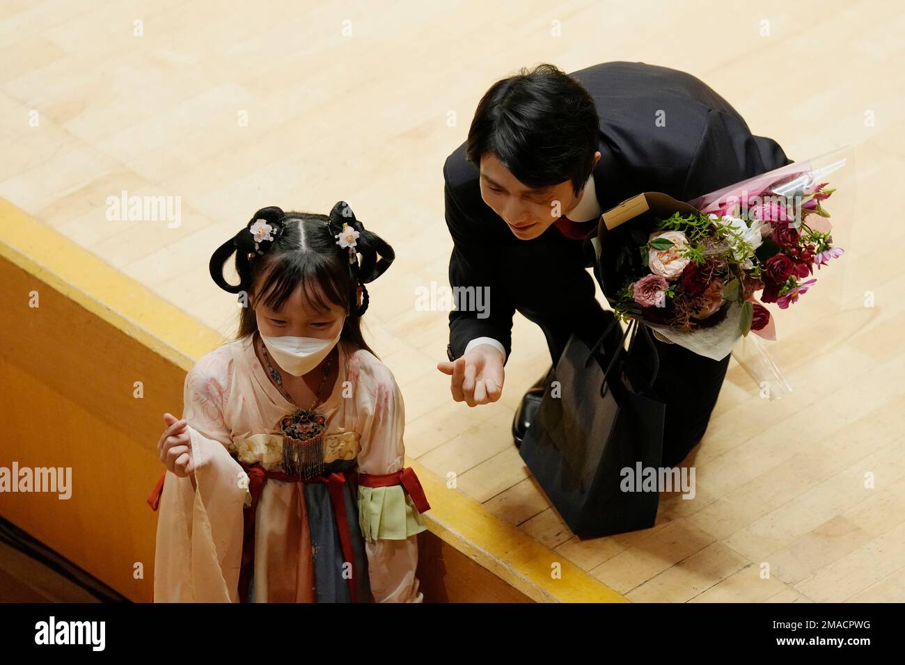 Figure skater Yuzuru Hanyu poses for a photo with a child at the beginning of an event ...