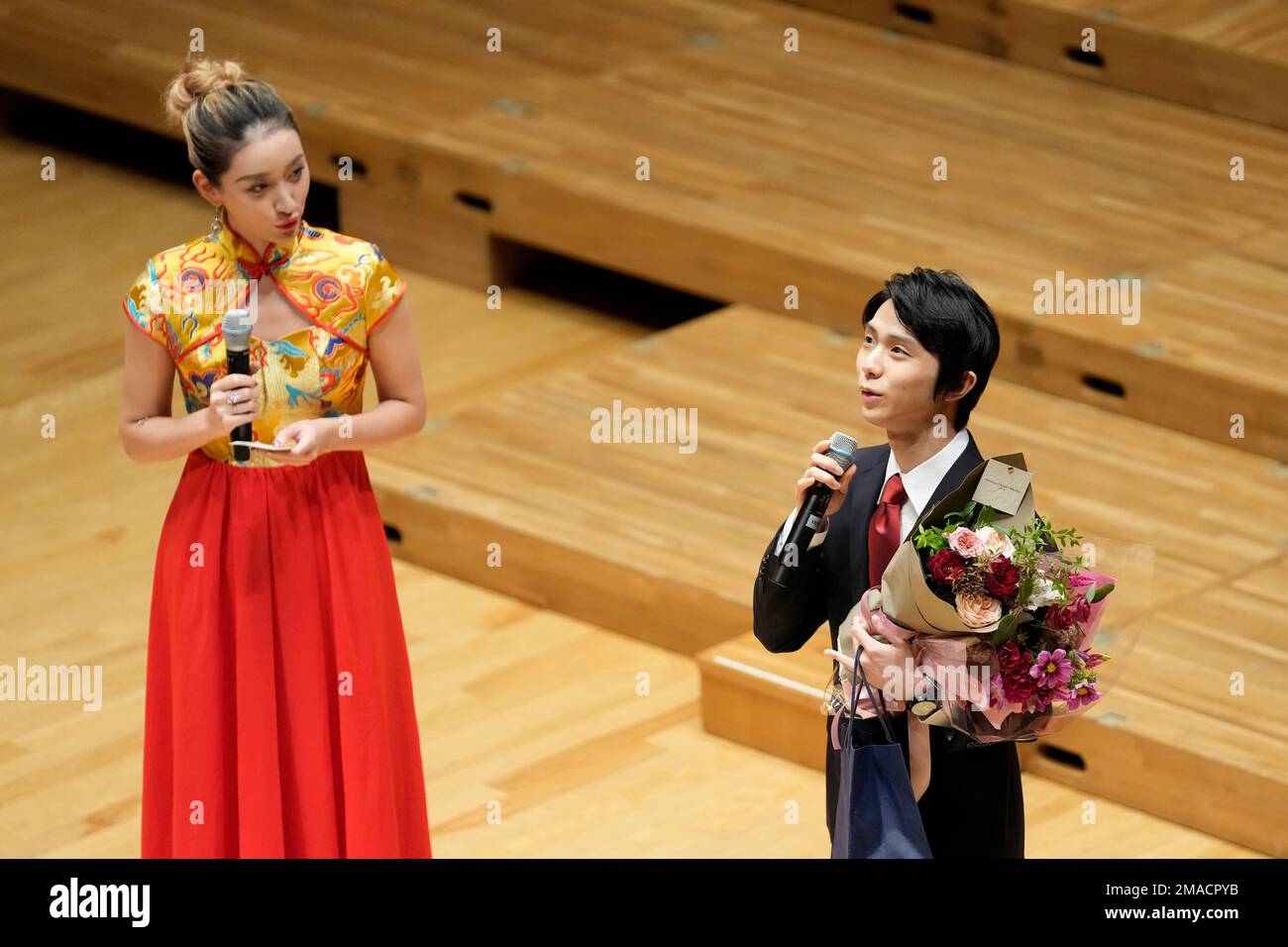 Chinese Japanese Erhu player Zhang Hina, left, listens as Japanese figure skater Yuzuru Hanyu ...