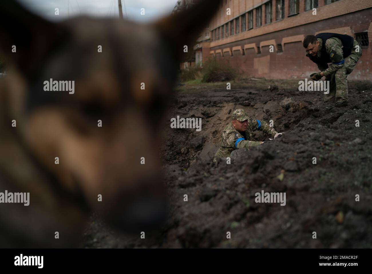 Ukrainian police officers collect fragments from a crater to determine ...