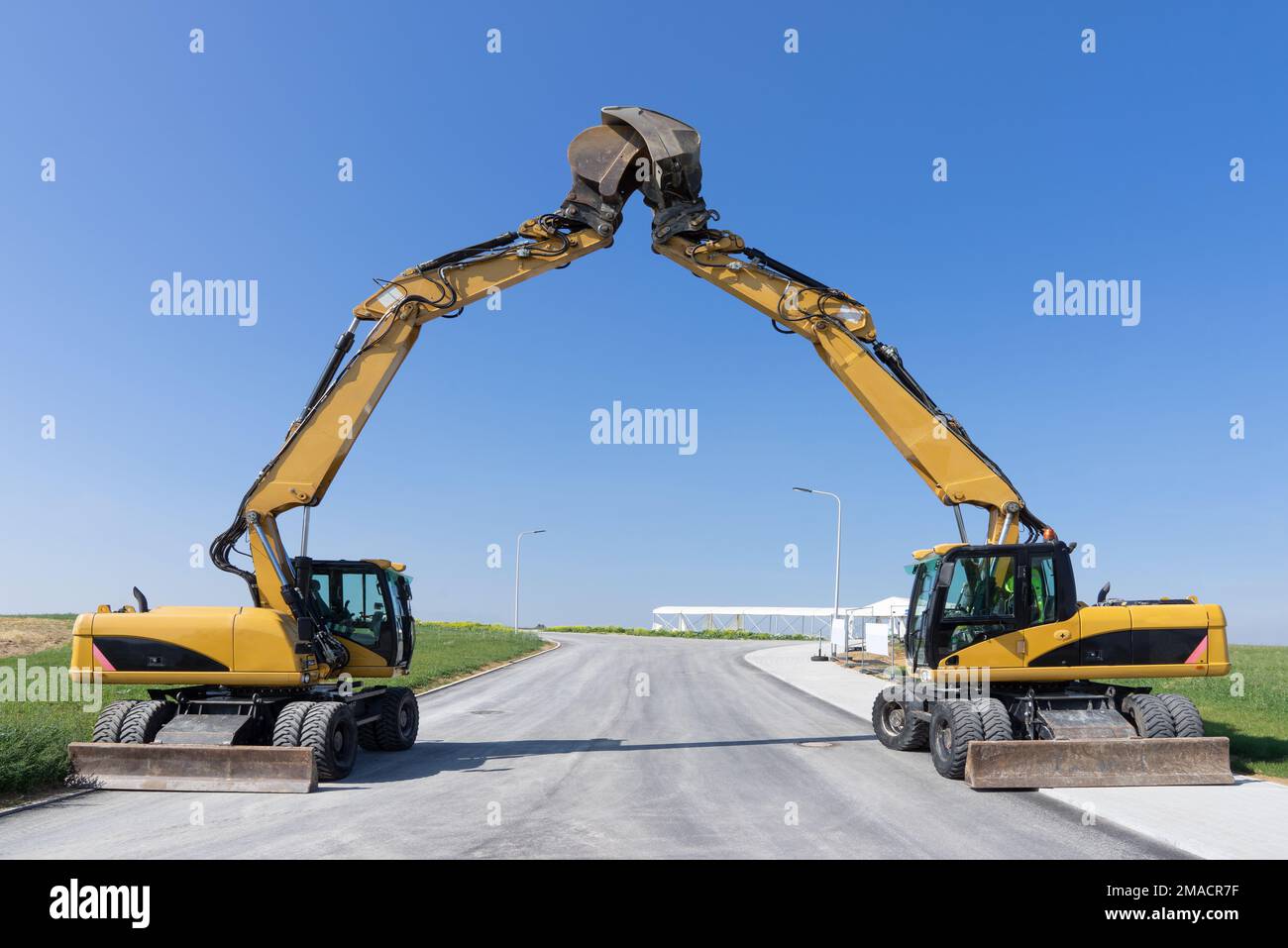 Two excavators use their shovels to form a gate Stock Photo - Alamy
