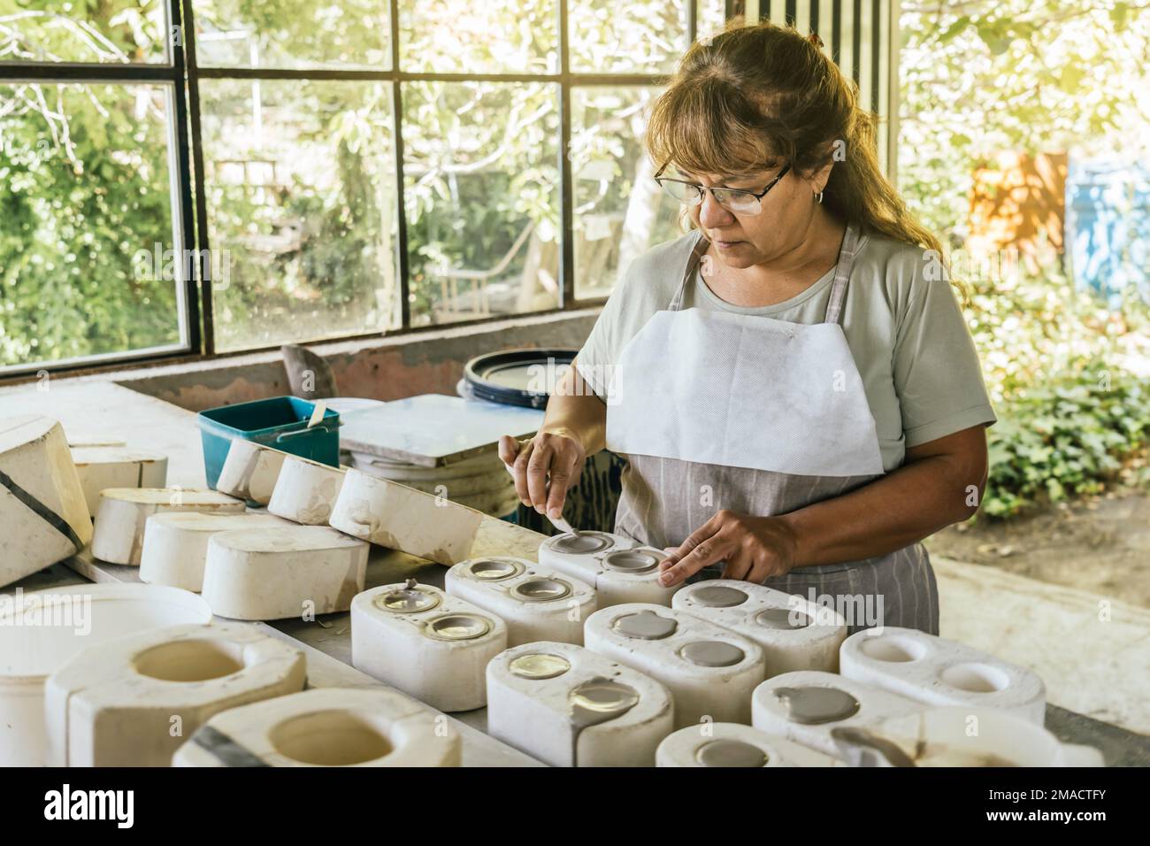 Ceramist with her hands dirty with clay. Woman ceramist working in ...