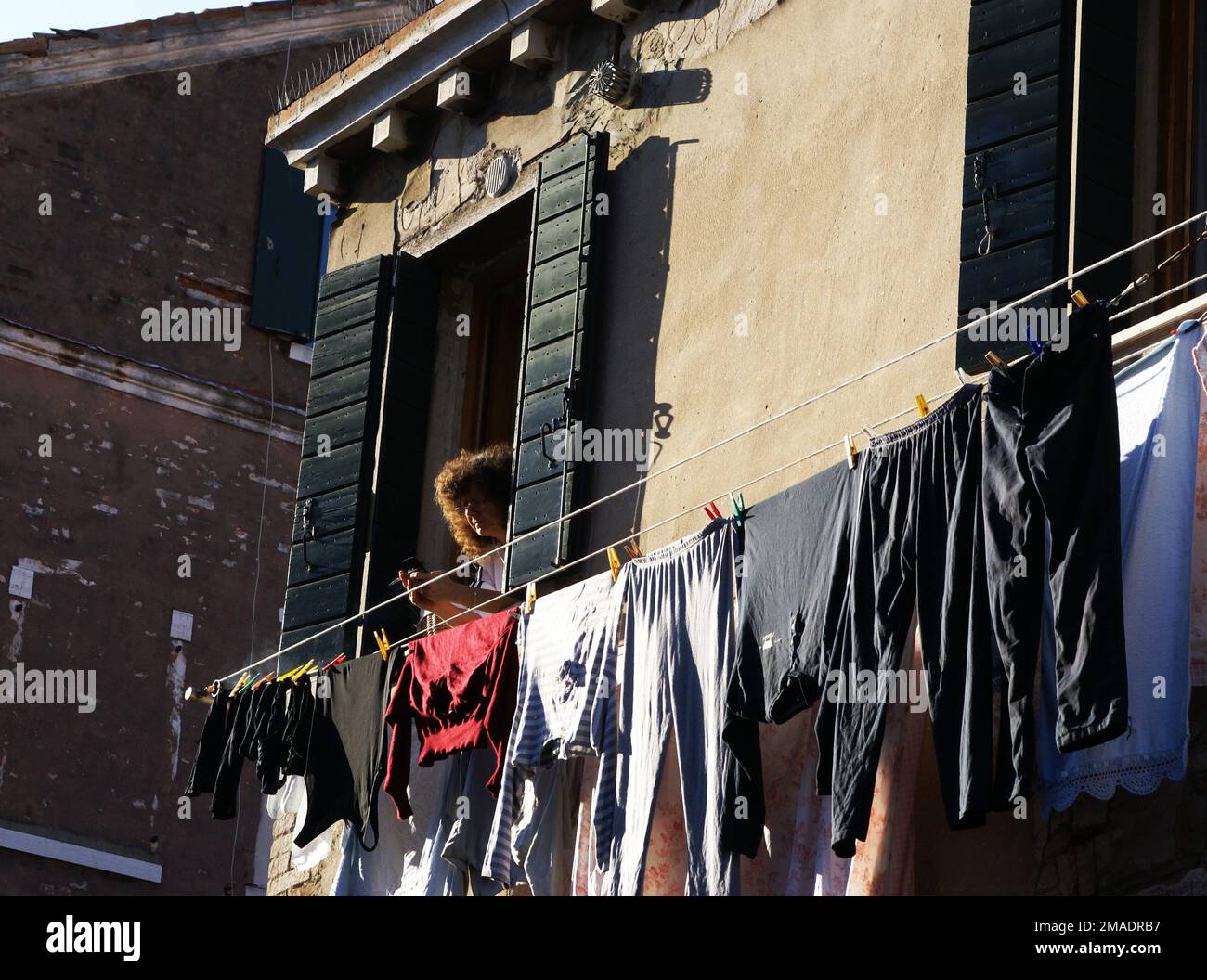 A local resident looks out of the window onto the street in Venice ...