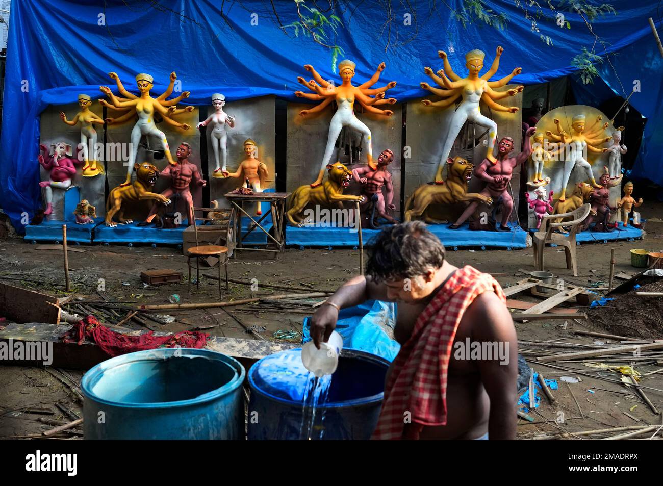 An artist takes out water for bath in between preparing idols of Hindu ...