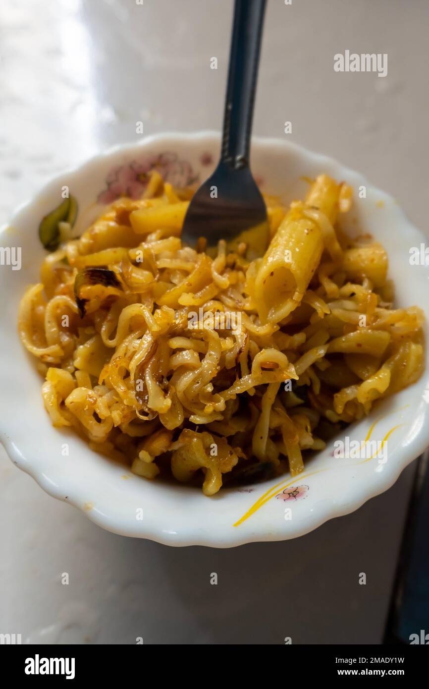 Portrait view of noodles with spoon in white bowl. Spicy asian instant ...