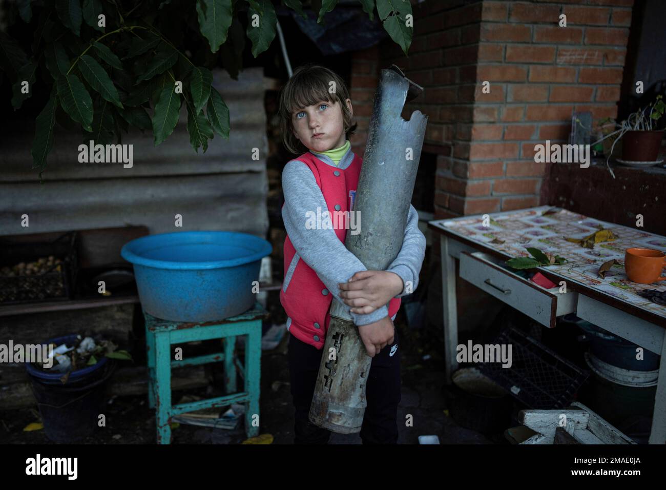 Veronika Tkachenko, 7, holds a piece of a Grad rocket which hit her family's house in the ...