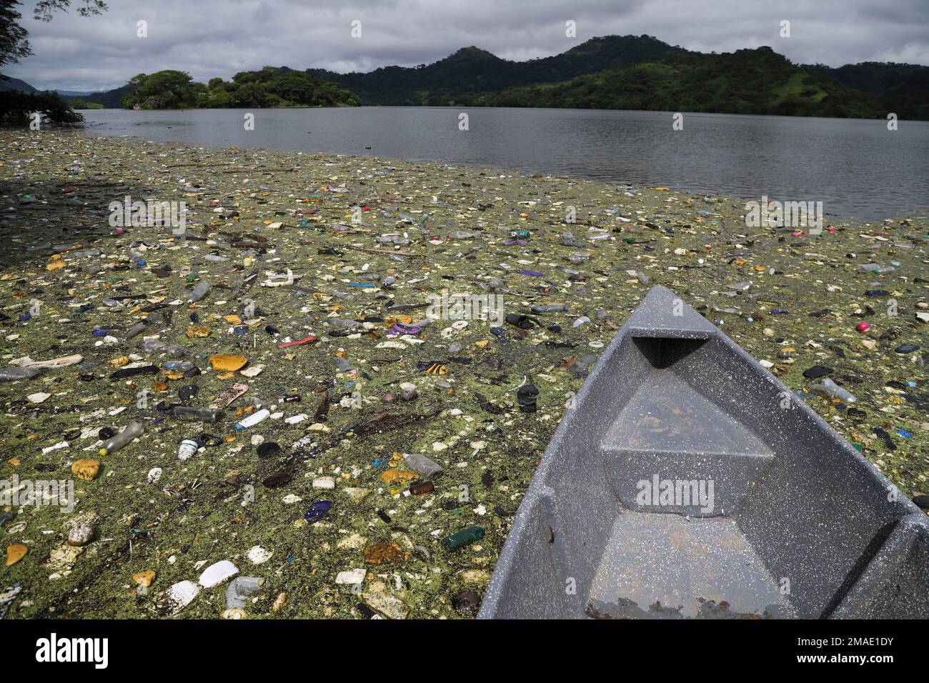 A boat moves through garbage floating on the basin of the Cerron Grande ...