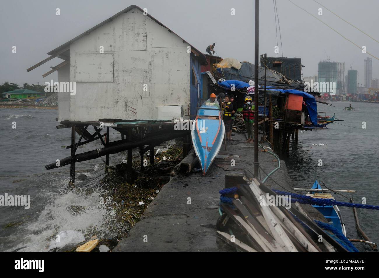 A resident secures the roof of his house at the seaside slum district ...
