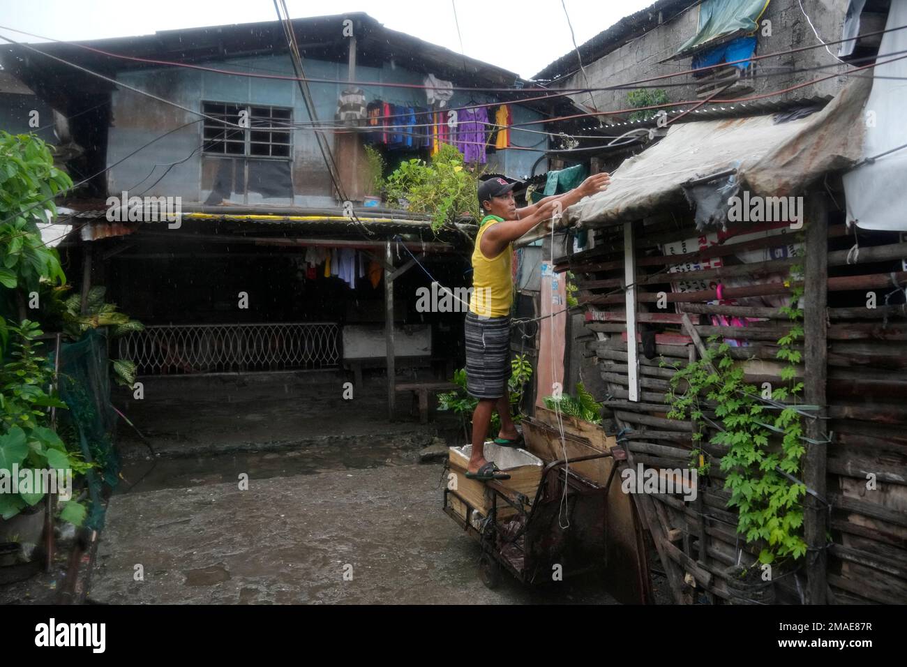 A resident secures his roof as Typhoon Noru approaches the seaside slum ...