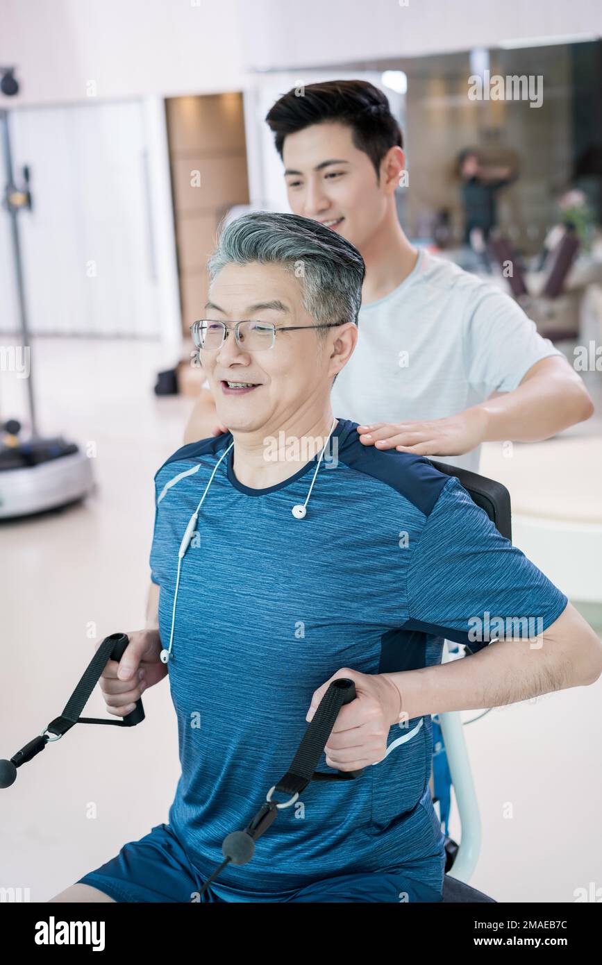 Under the guidance of the elderly man in personal training in the gym ...
