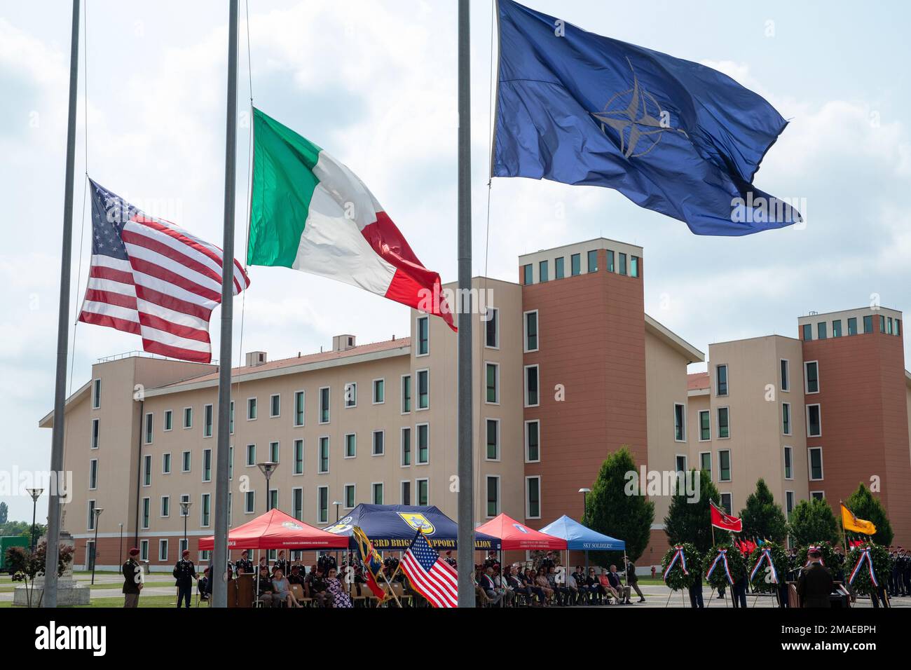 From left to right, The U.S., Italian, and NATO flags are displayed at ...