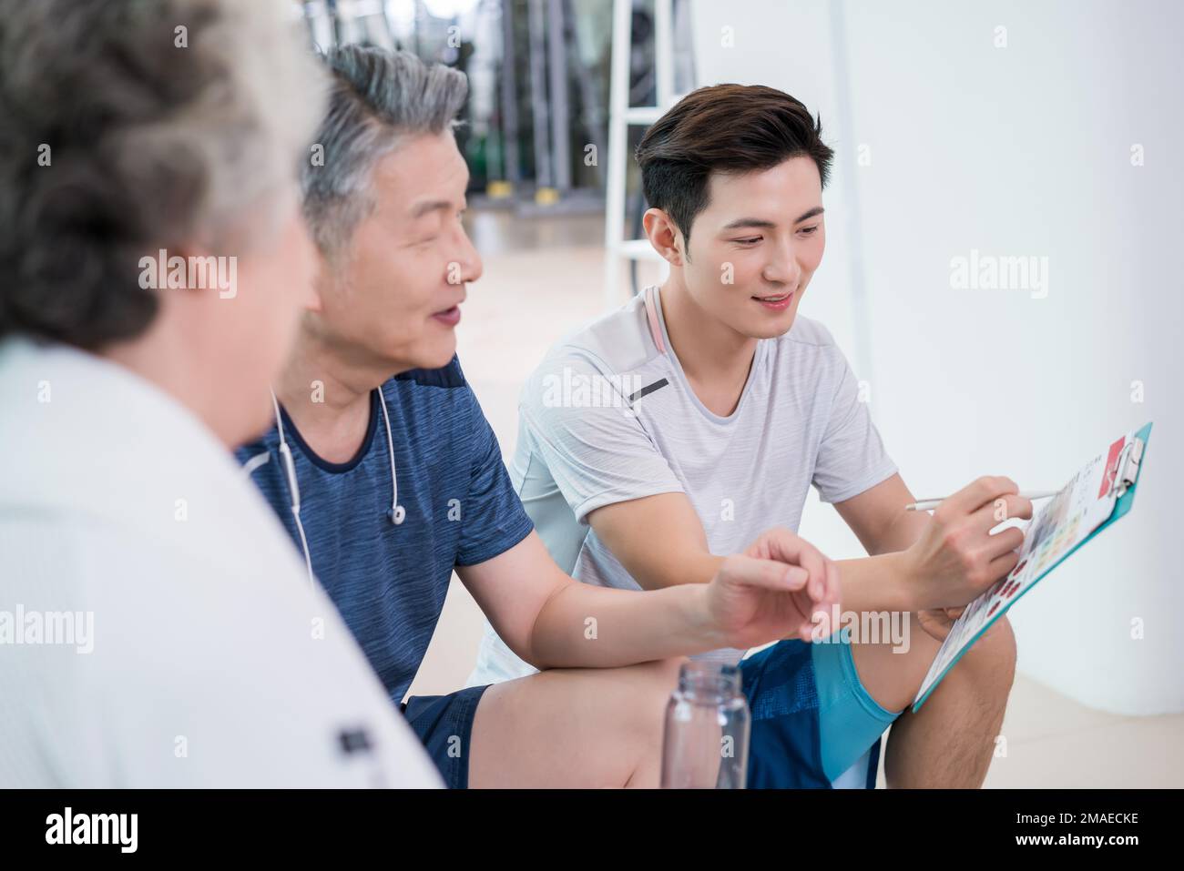 Elderly couple under the guidance of personal training in the gym for a ...