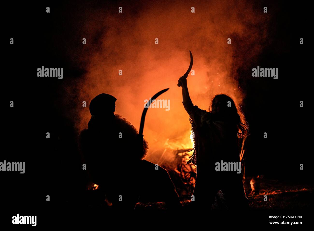 Children engage in a sword fight, backdropped by a campfire, during the ...