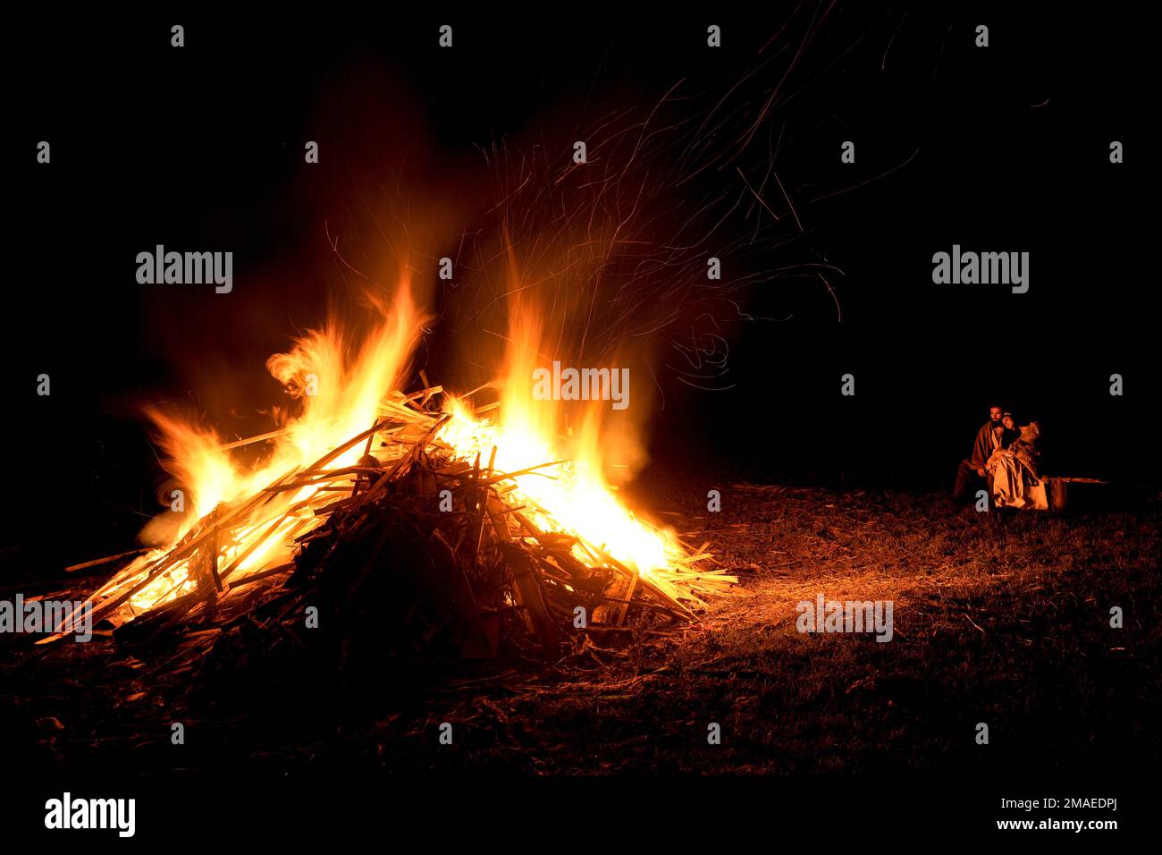 A couple sits by a campfire, during the Romula Fest historic ...