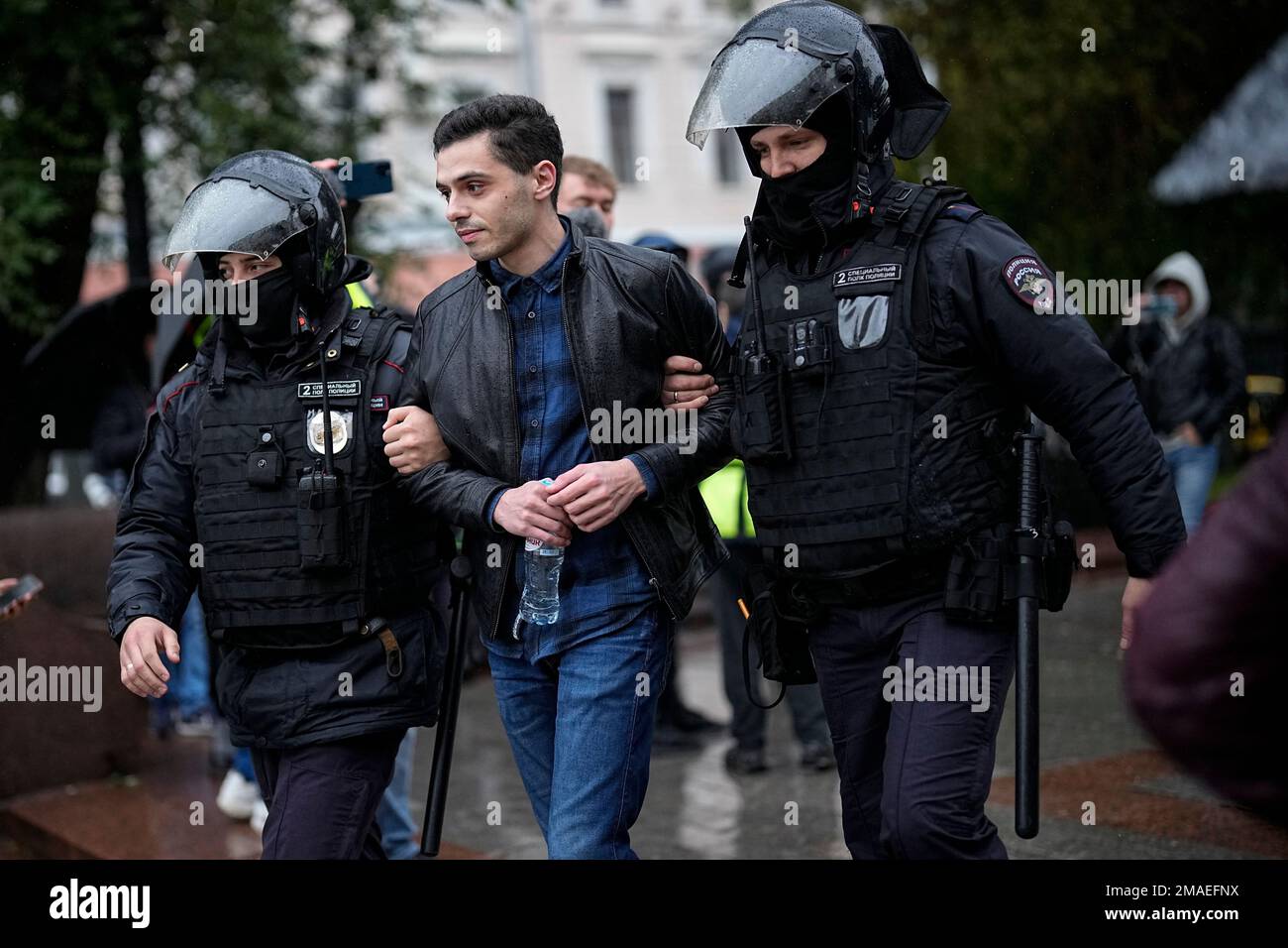 Police officers detain a demonstrator during a protest against a ...