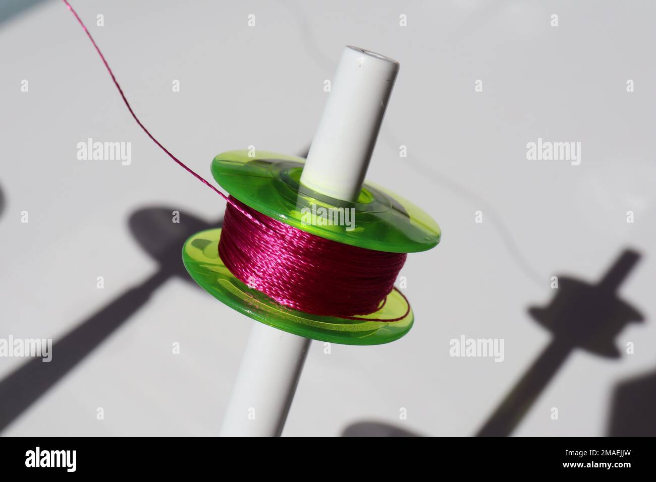 Macro of deep-pink rayon yarn on a green semi-transparent plastic ...