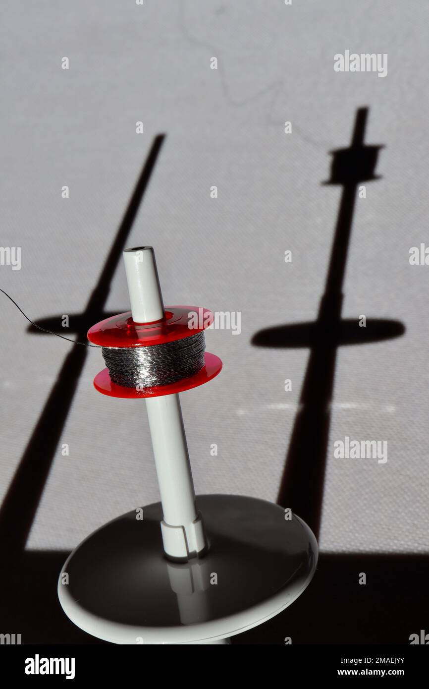 Macro of silver metallic yarn on a semi-transparent deep-pink plastic ...