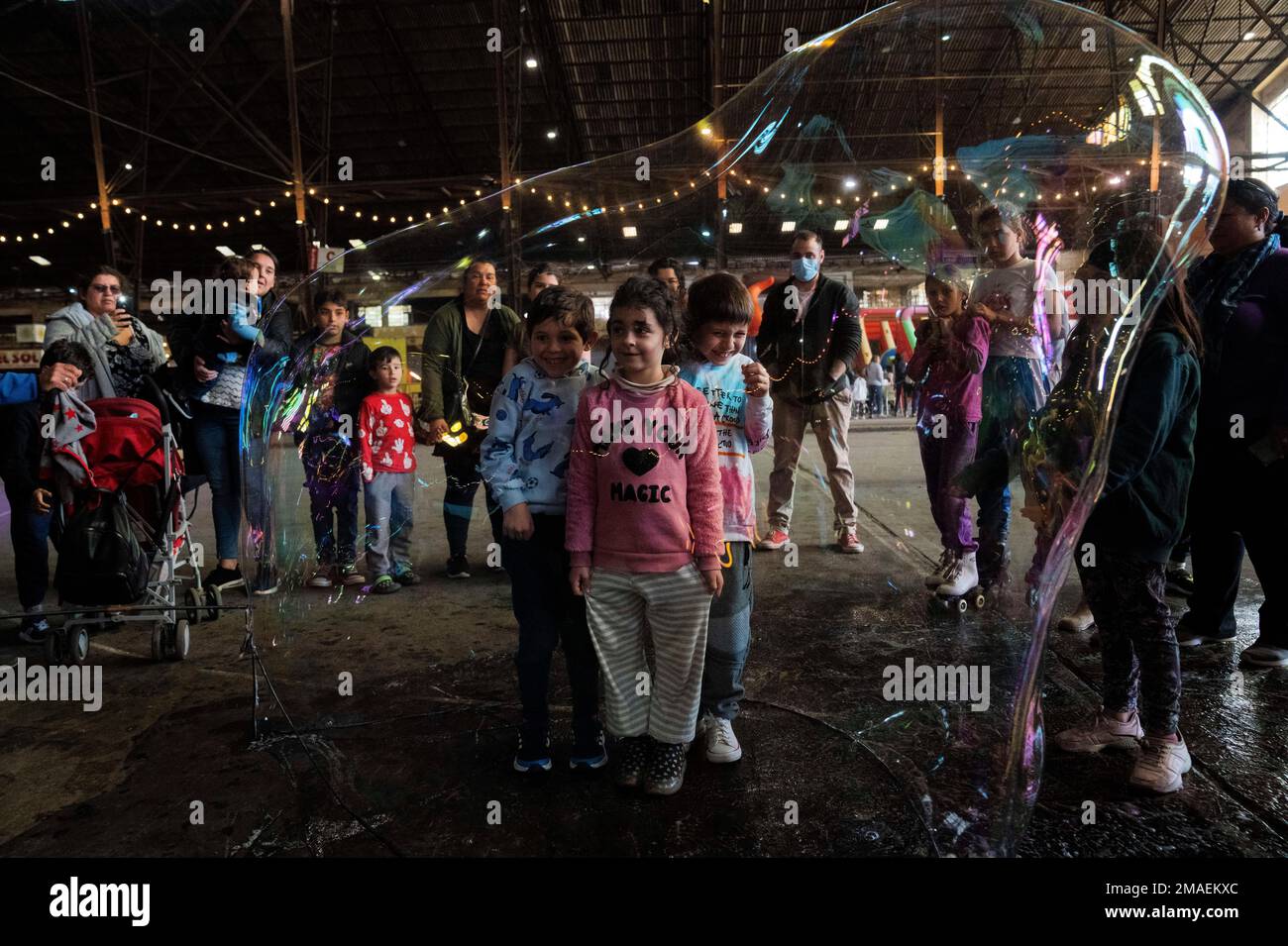 Children pose for a photo inside a giant soap bubble during a spring ...