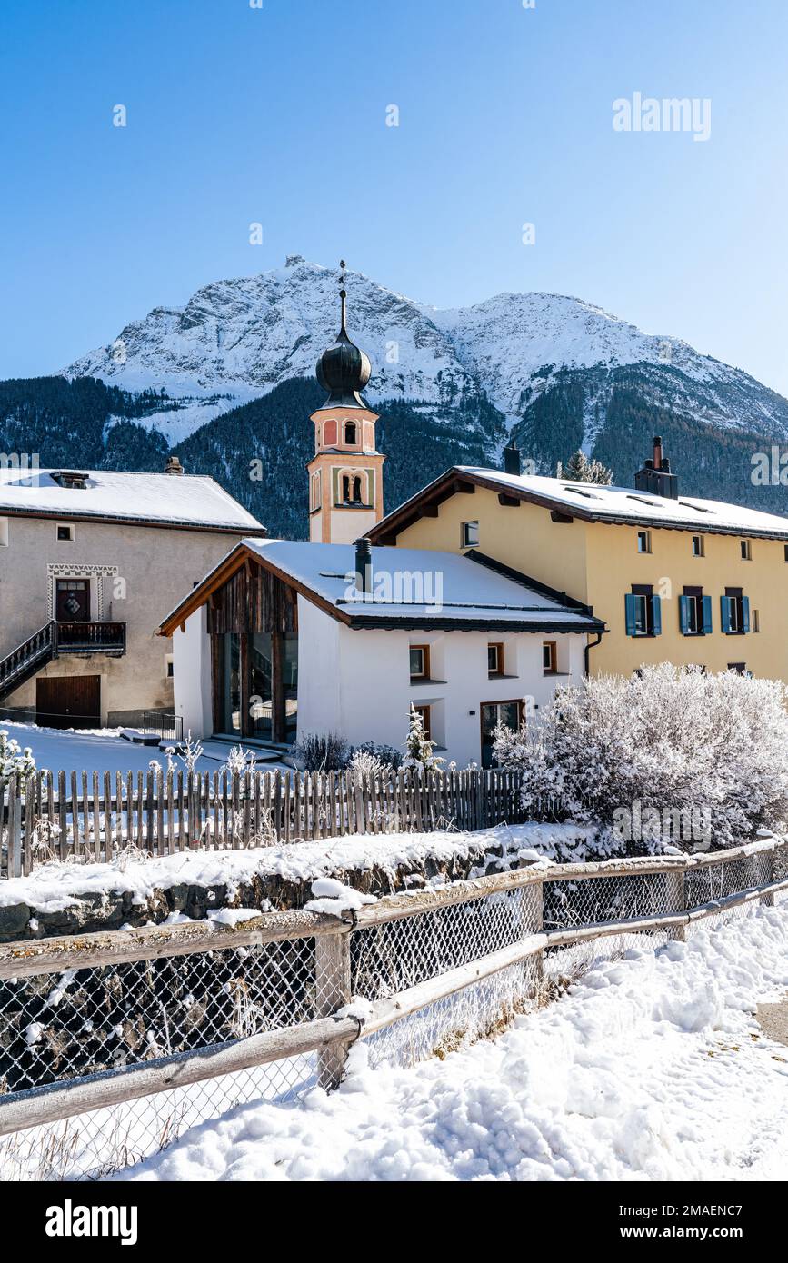 Small village with church covered in snow surrounded by mountains ...
