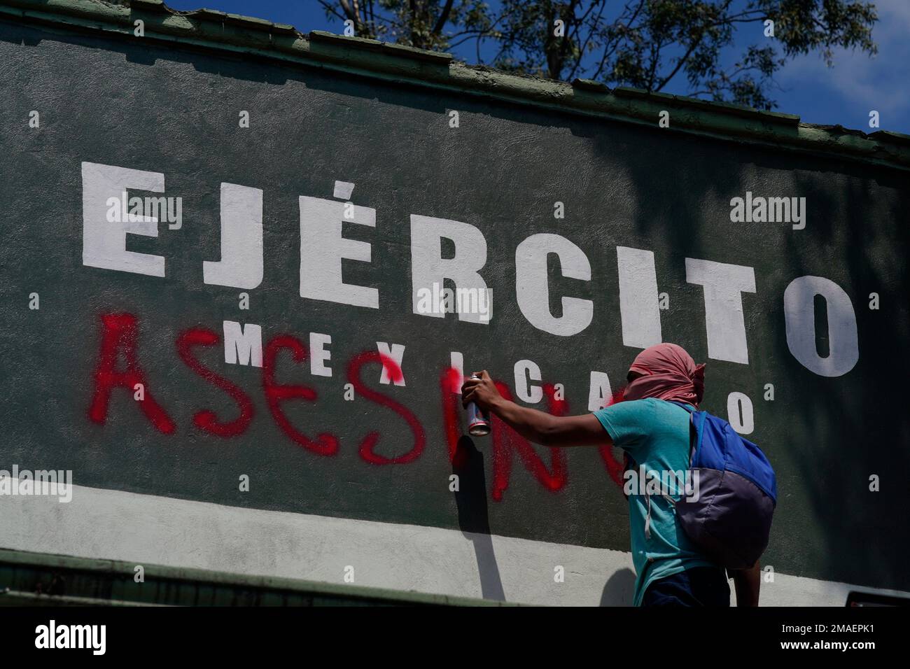 A demonstrator uses red spray paint, symbolizing blood, to write the ...
