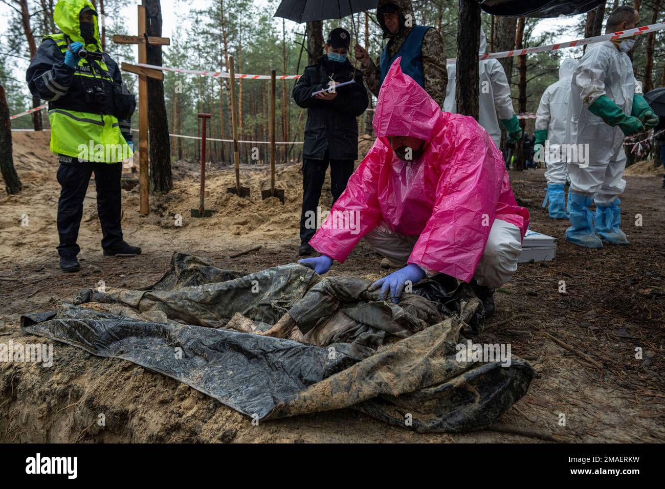 An expert examines the body of a civilian during exhumation in the ...