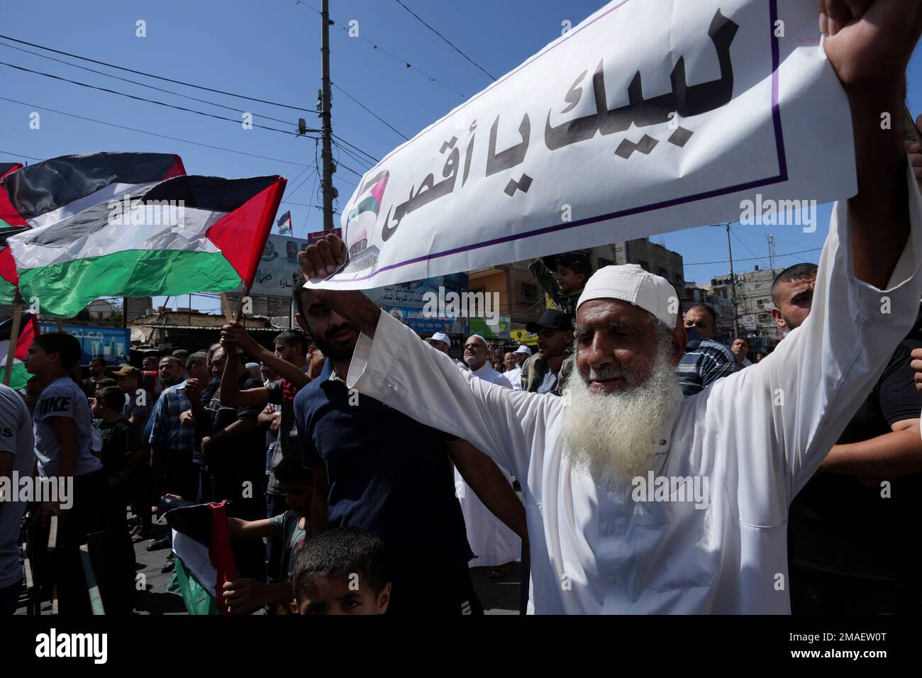 An elderly man holds a placard reads "for your services Al-Aqsa ...