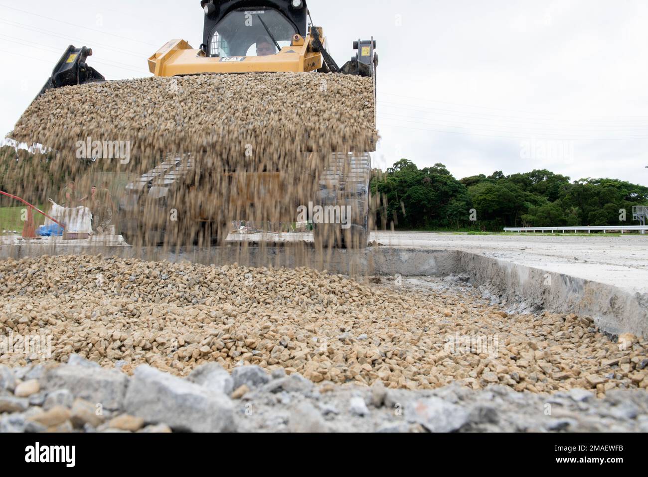 A bulldozer dumps gravel into a crater during a joint airfield damage ...
