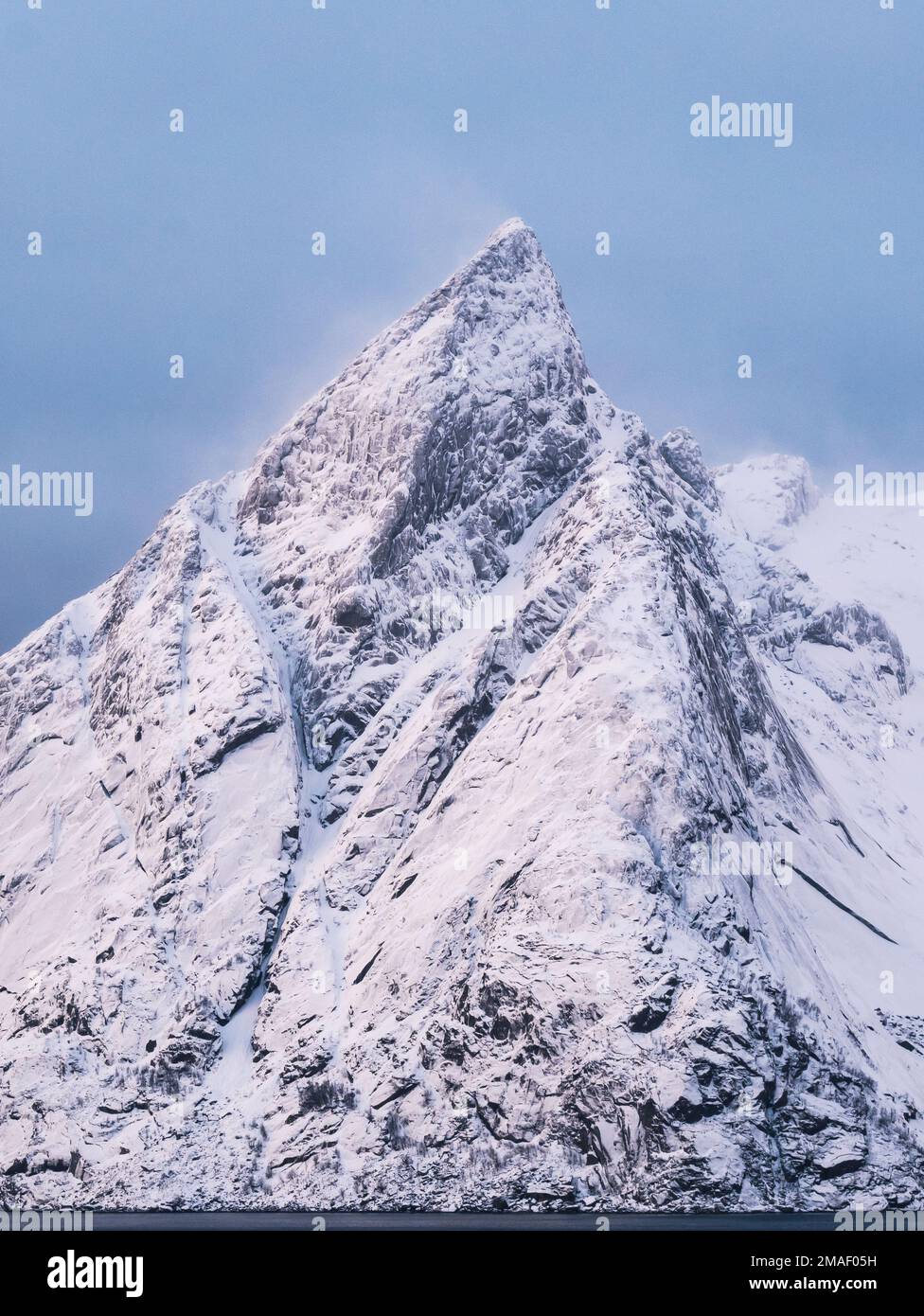 Sharp winter snowy mountain peak in Reine, Lofoten fjord, Norway Stock ...