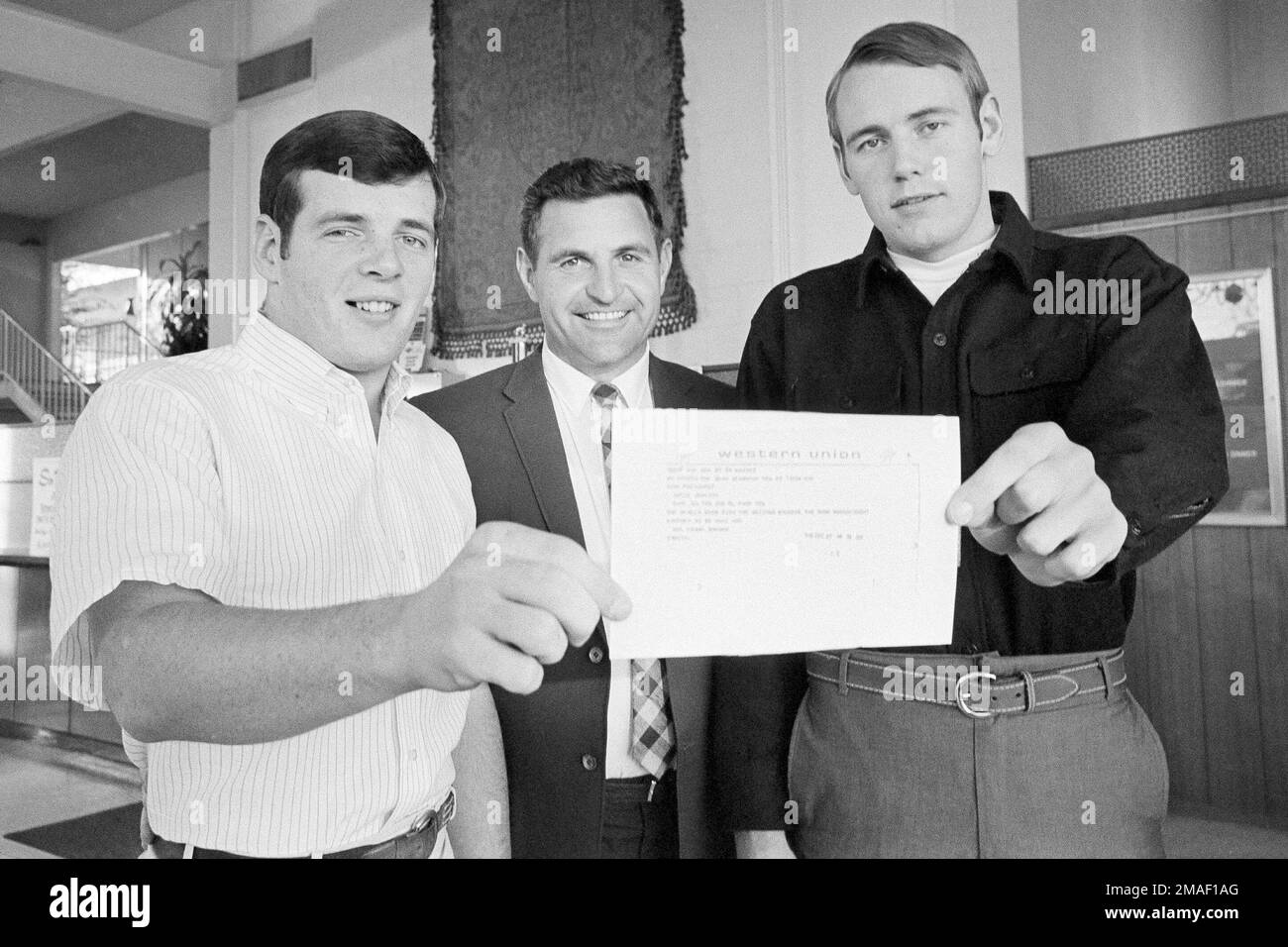 University of Arizona football coach Darrell Mudra is flanked by his ...