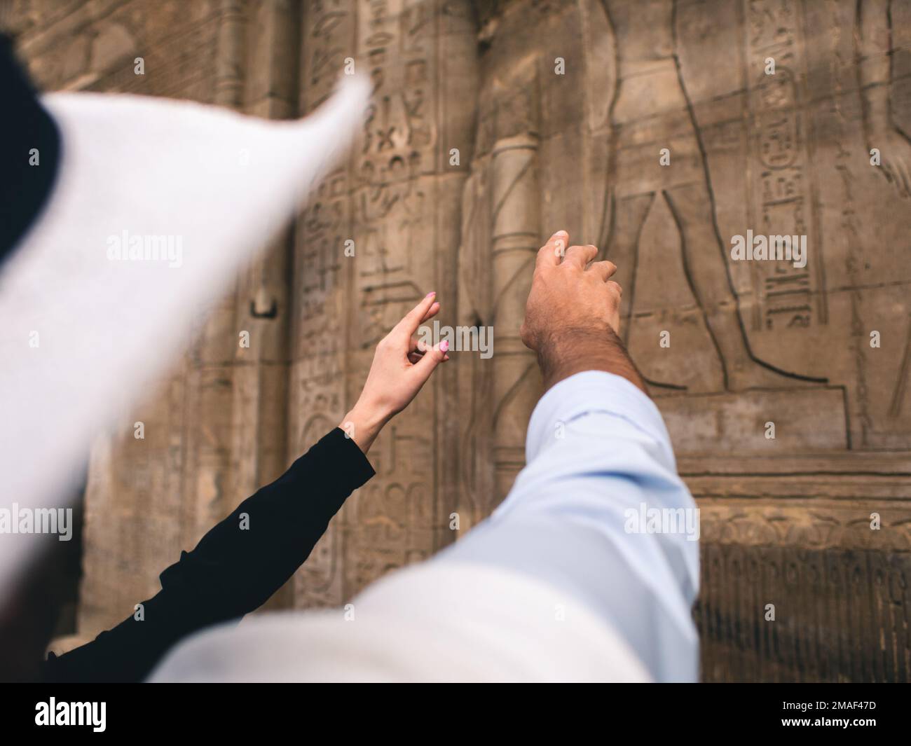 Hands of white caucasian man and woman pointing at Egyptian hieroglyphs ...