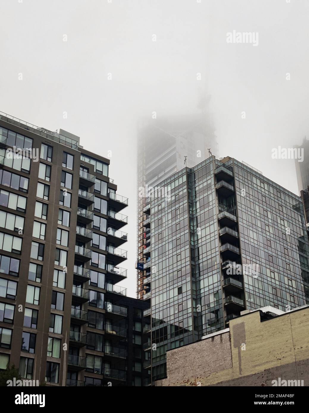 A vertical shot of two modern residential buildings with glass windows ...