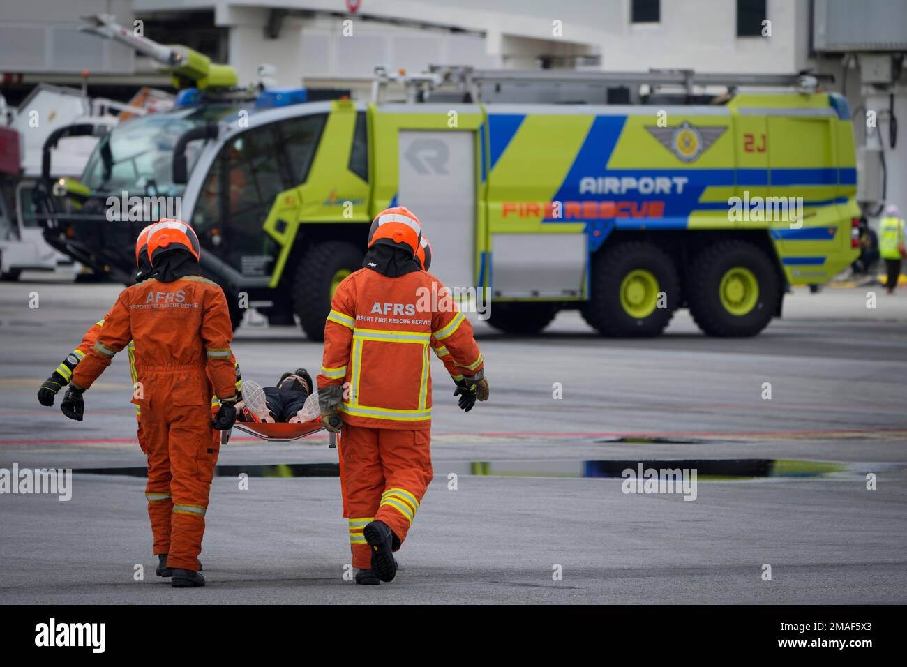 Fire and rescue personnel carry a volunteer during an emergency drill ...