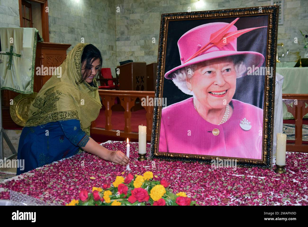 A portrait of the late Queen Elizabeth II is on display as woman pay ...
