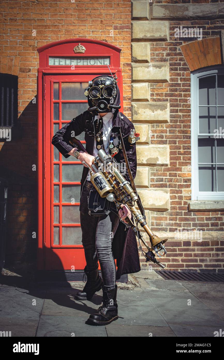A retro futuristic steampunk holding a weapon standing in front of an ...