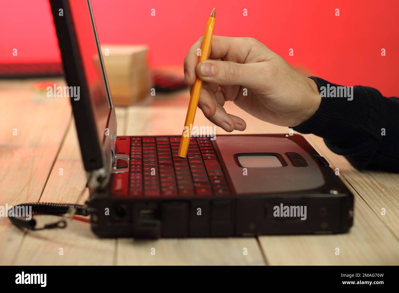 punching letters with a pen on the keyboard of an old laptop by a ...