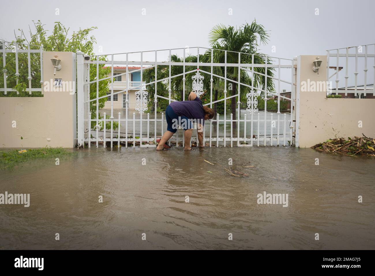 A woman clears debris on her property flooded by Hurricane Fiona in ...