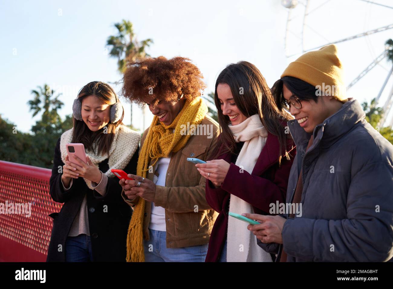 Four friends of diverse nationalities gathered outdoors, standing in a ...