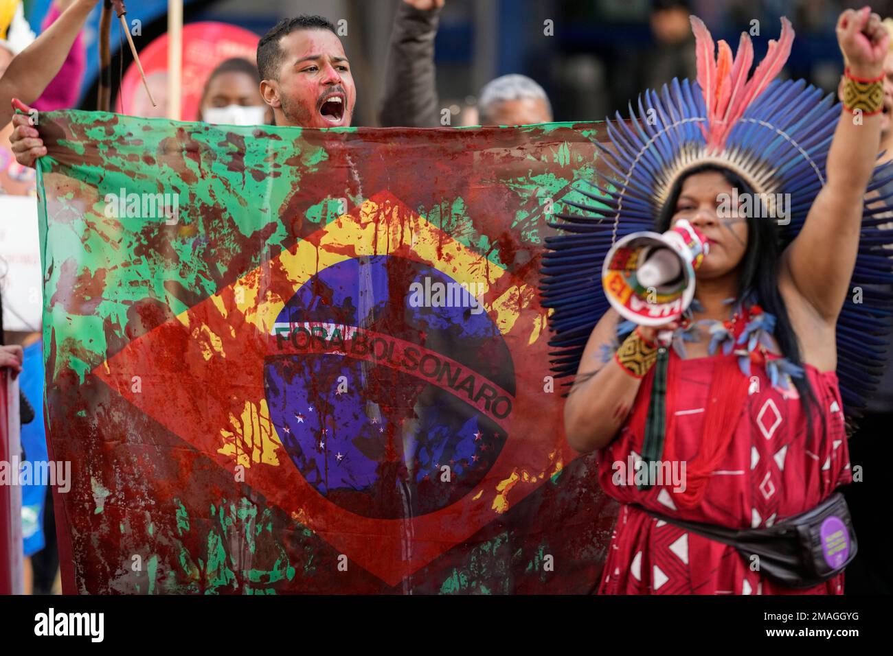 An Indigenous man holds a Brazilian national flag painted in red to ...