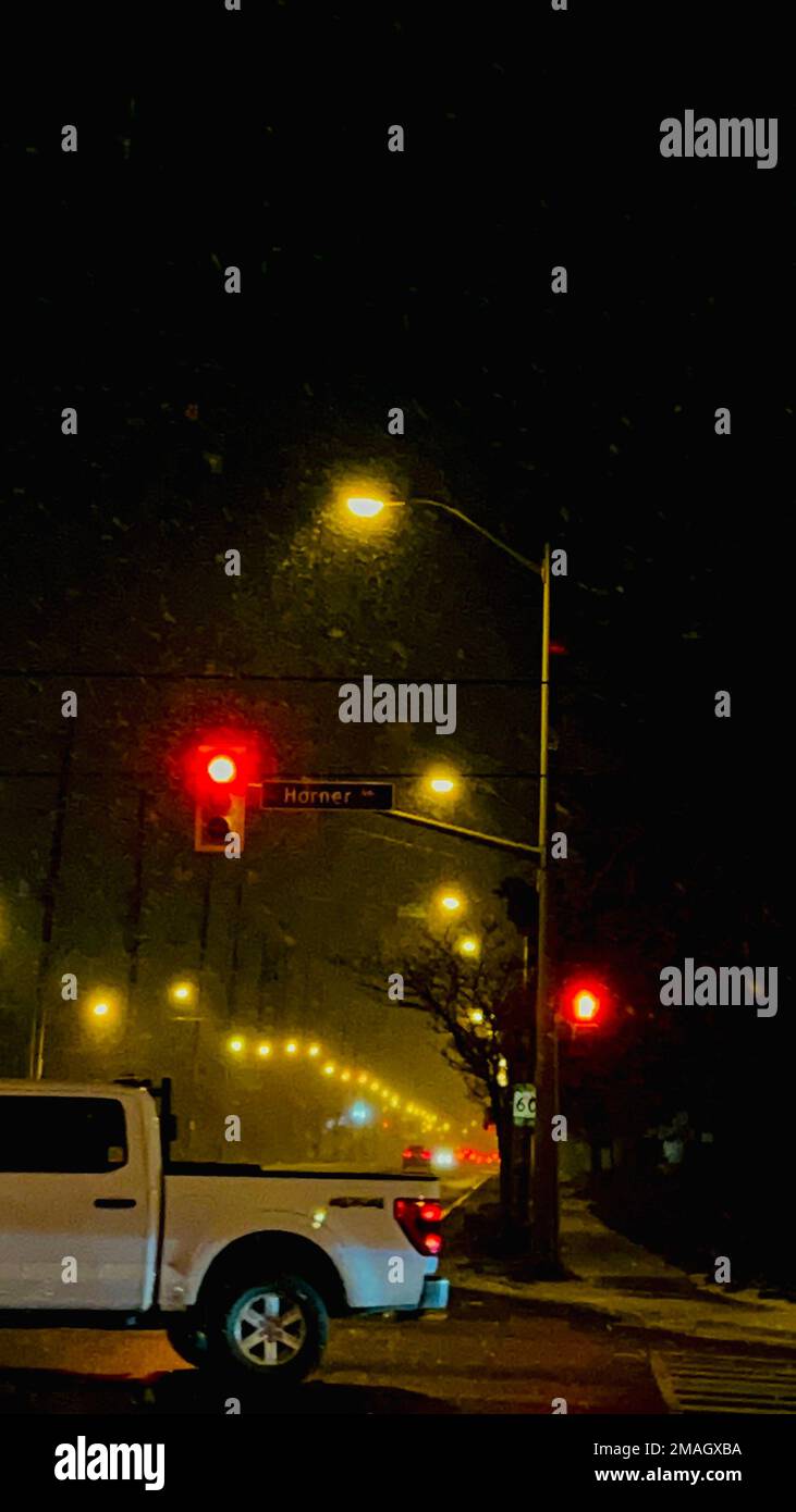 A vertical side view of white truck in the street at night with yellow ...