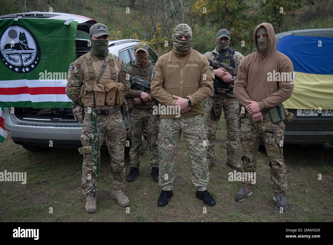 Volunteer soldiers of a Chechen unit pose with a flag of Chechen ...
