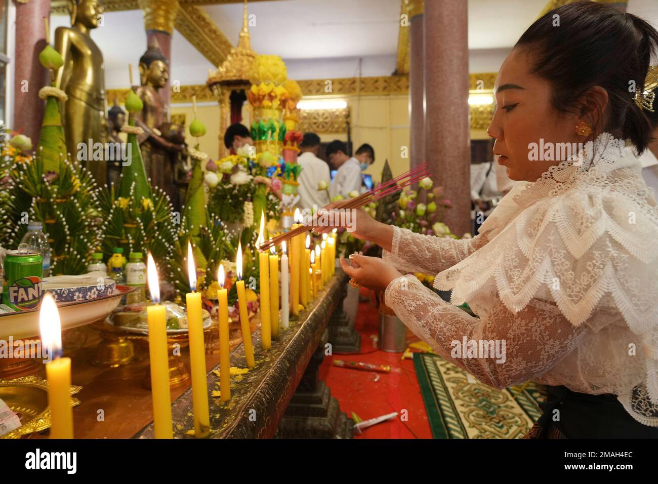 A Cambodian devotee lights candles and incense sticks during a ...