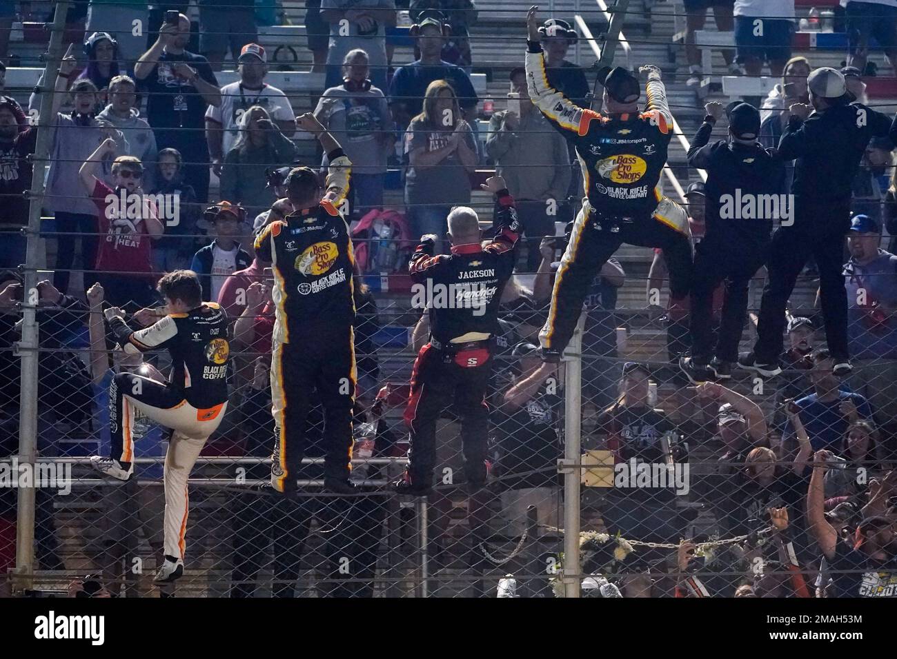 Noah Gragson, left, climbs the fence with his crew after winning a ...