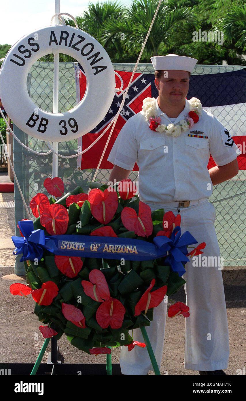 A sailor stands beside a wreath from the state of Arizona, displayed at ...