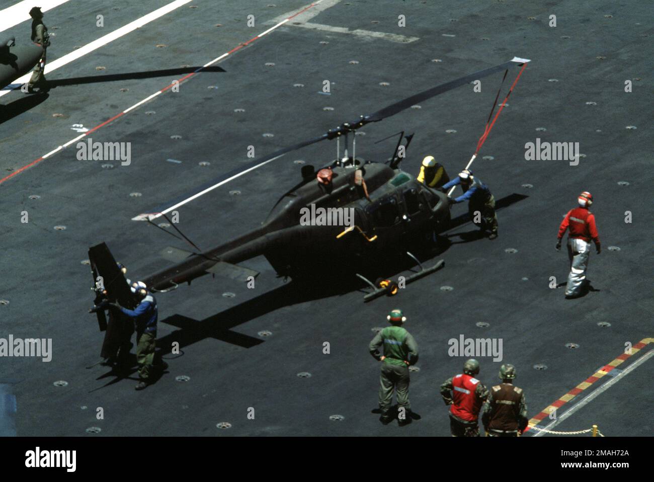 Flight deck crews on board the carrier repositions an OH-58 Kiowa ...
