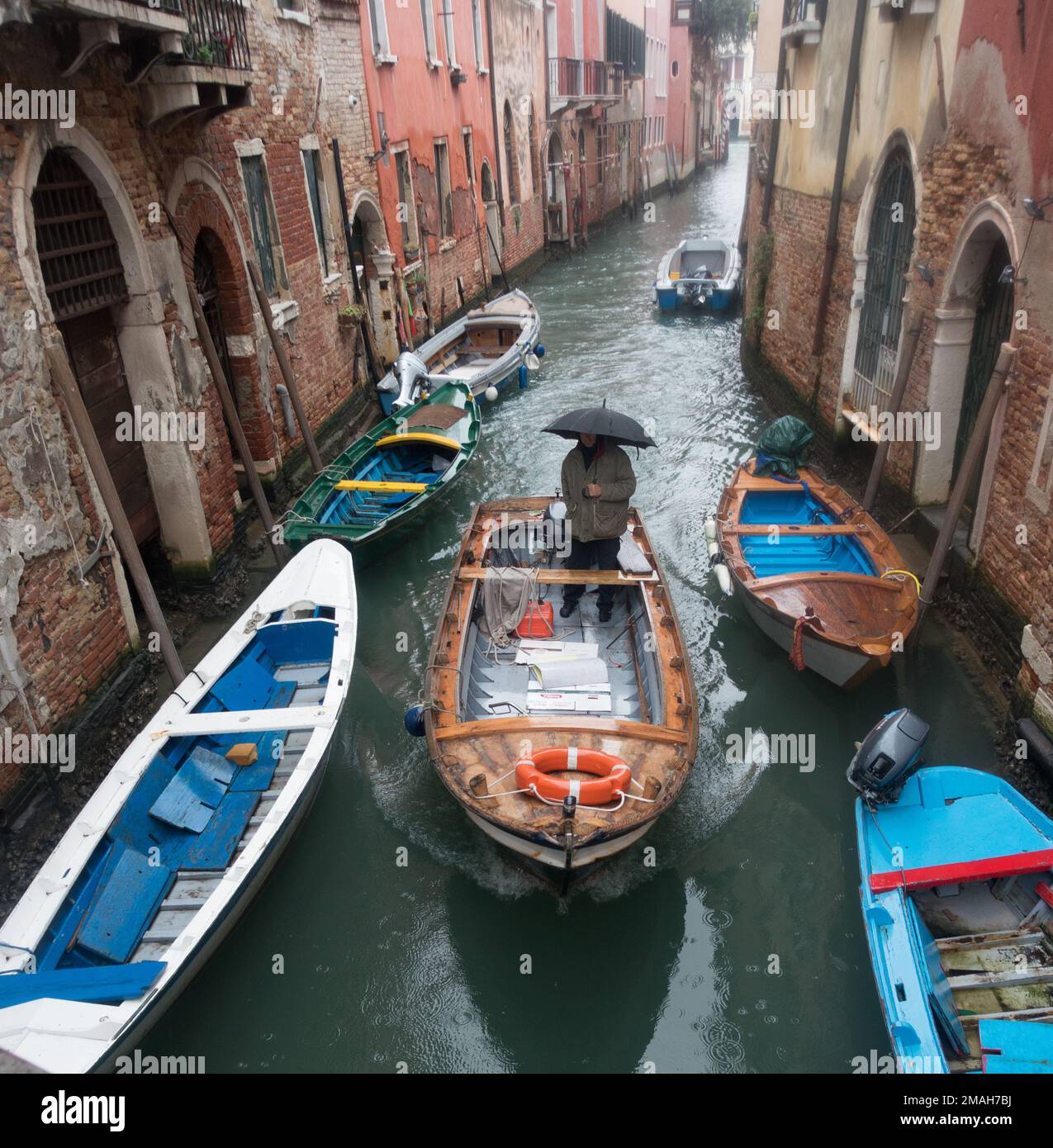 Canal with boats and one person with umbrella in the rain, Venice, Italy Stock Photo - Alamy