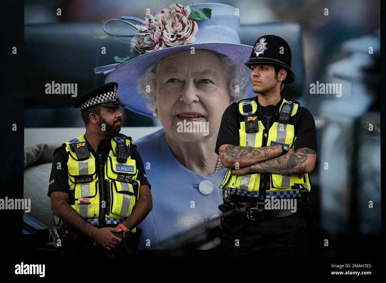 Police officers are backdropped by a photograph of Queen Elizabeth II ...